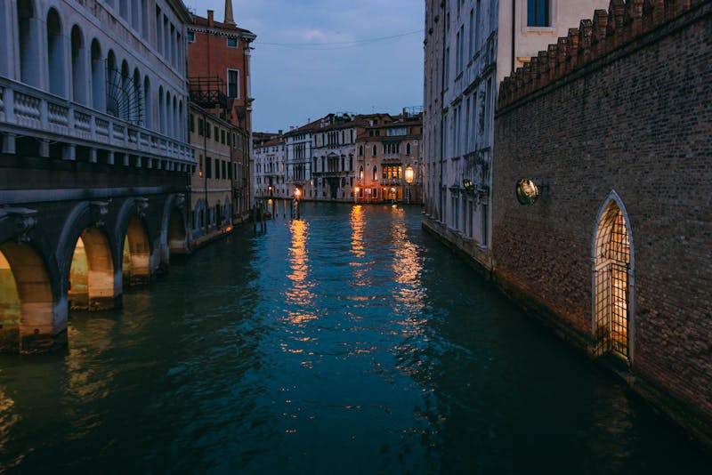 Venetian canal at twilight with warm lights reflecting on the water