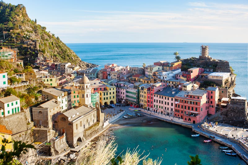 Stunning aerial view of Vernazza showing the compact village nestled between steep green hillsides and the blue Ligurian Sea
