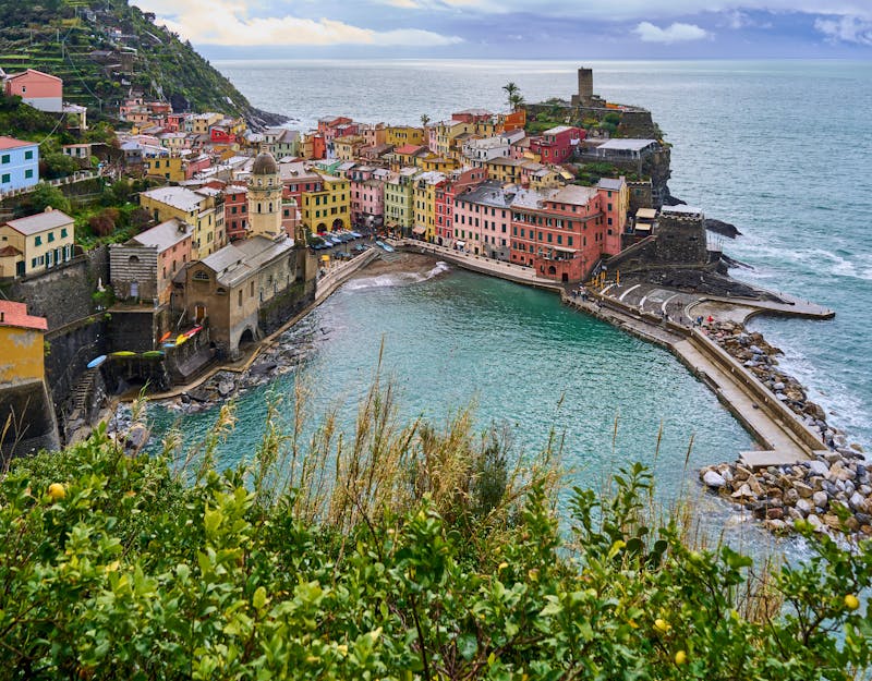 Panoramic view of Vernazza with its colorful buildings perched on cliffs above the turquoise Mediterranean Sea