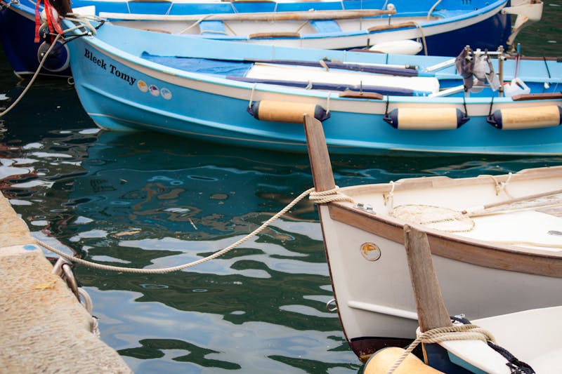 Colorful fishing boats moored in the small harbor of Vernazza, Cinque Terre, with pastel-colored buildings rising behind them