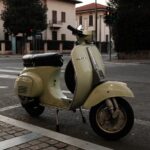 Classic Vespa scooter parked on a quiet cobblestone street in Tuscany
