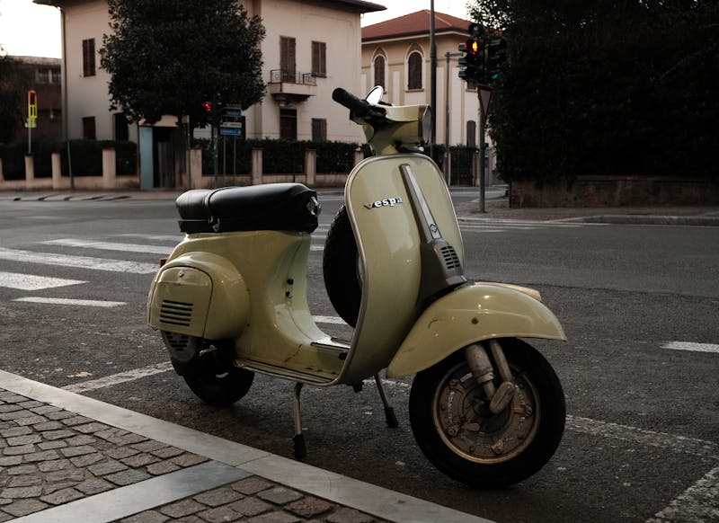 Classic Vespa scooter parked on a quiet cobblestone street in Tuscany