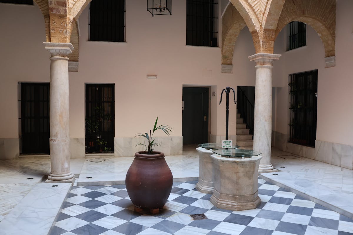 An elegant Andalusian courtyard with marble arches, columns, and patterned flooring