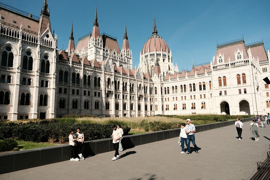 View of the iconic Budapest Parliament with people enjoying the riverfront