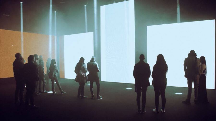 People exploring a large immersive digital art exhibition with illuminated screens