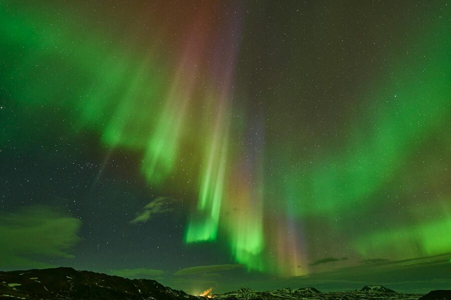 Vivid aurora borealis dancing over Icelandic landscape, striking night spectacle.