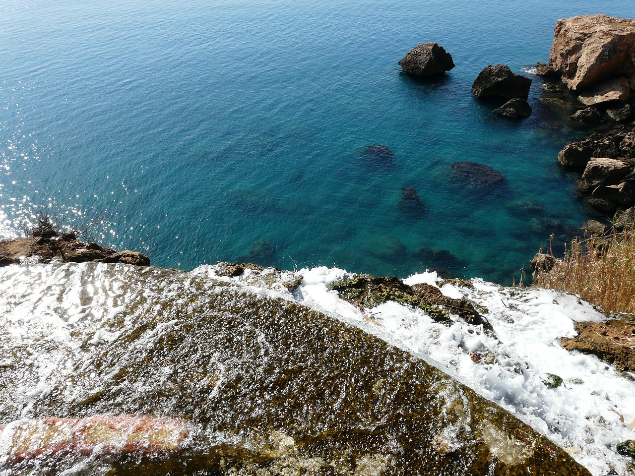 Waterfall cascading into the sea from coastal cliff
