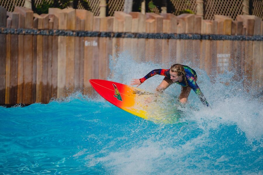 Woman surfing a wave on a colorful surfboard in an outdoor wave pool