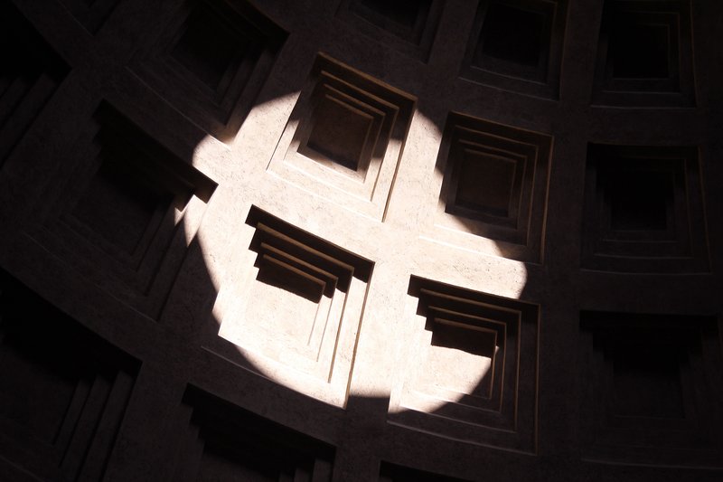 A beam of sunlight streaming through the Pantheon oculus creating a visible shaft of light in the interior