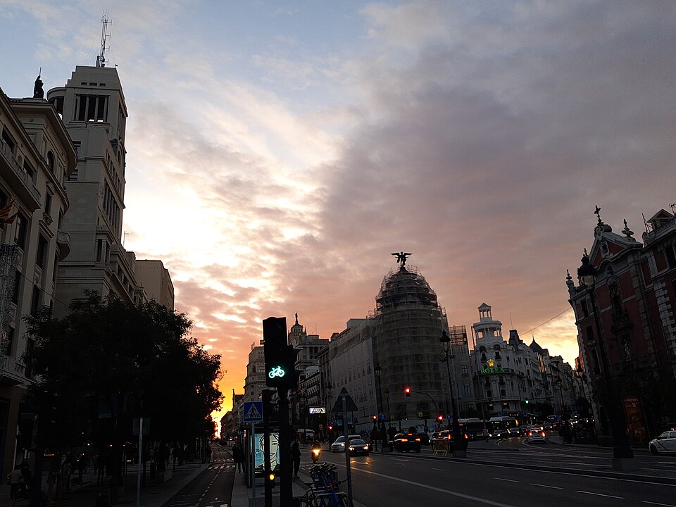 Golden sunset light illuminating Gran Via boulevard in Madrid with historic buildings