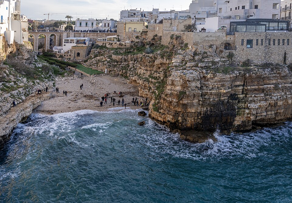 The famous Lama Monachile pebble beach cove framed by high cliffs and the old bridge in Polignano a Mare