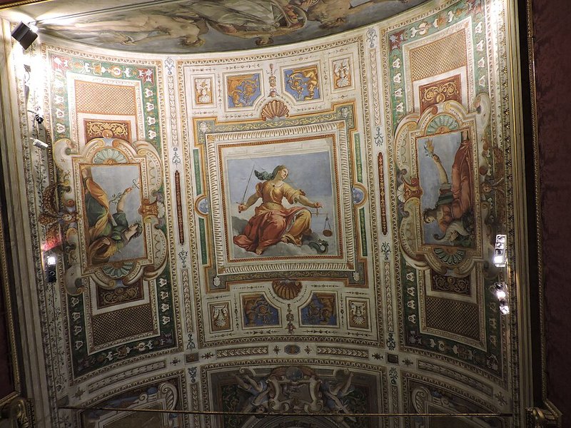 Interior view of the Palatine Gallery showing ornate gold frames, Renaissance paintings, and marble busts