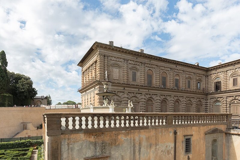 Wide view of the full front facade of Palazzo Pitti from the piazza showing the stone Renaissance architecture