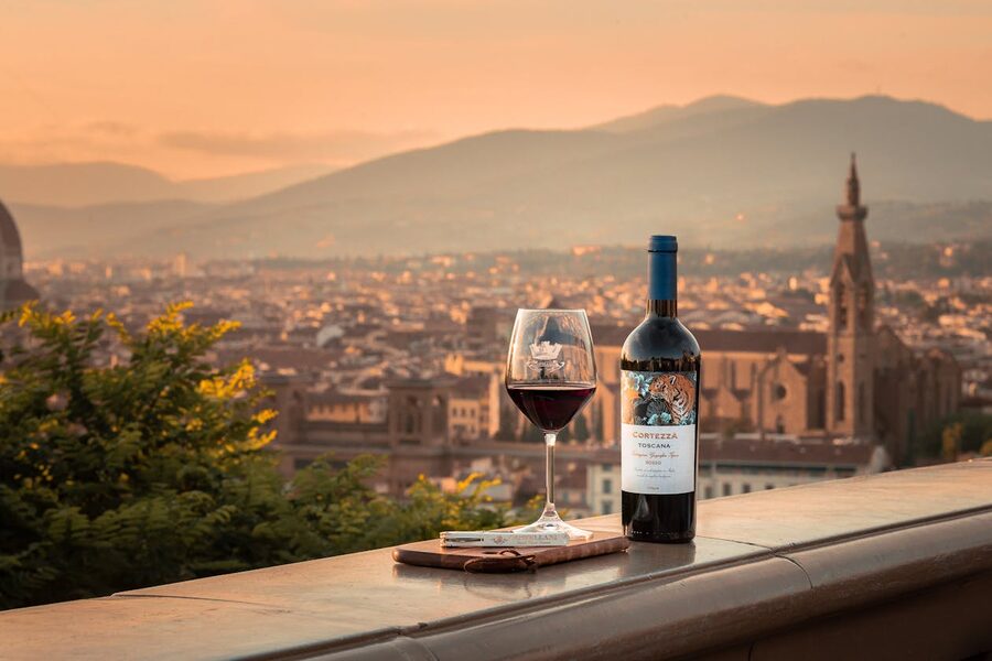 Glass of red wine on a terrace with Florence cathedral dome and skyline in golden sunset light