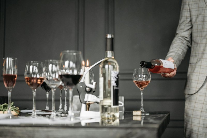 A sommelier pouring rose wine into a tasting glass during a wine tasting session