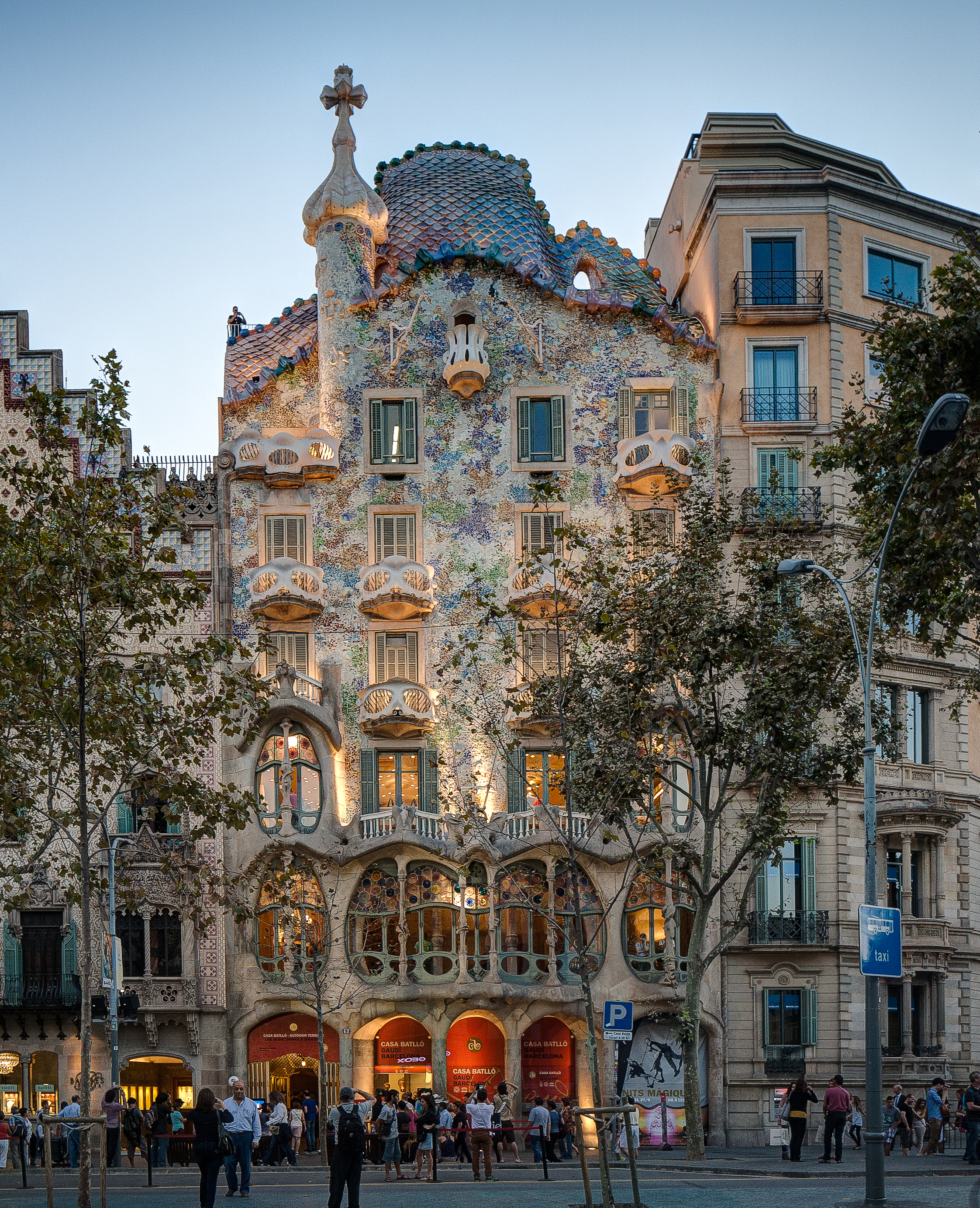 Full exterior view of Casa Batllo showing its organic facade, skull-like balconies, and colorful mosaic tiles