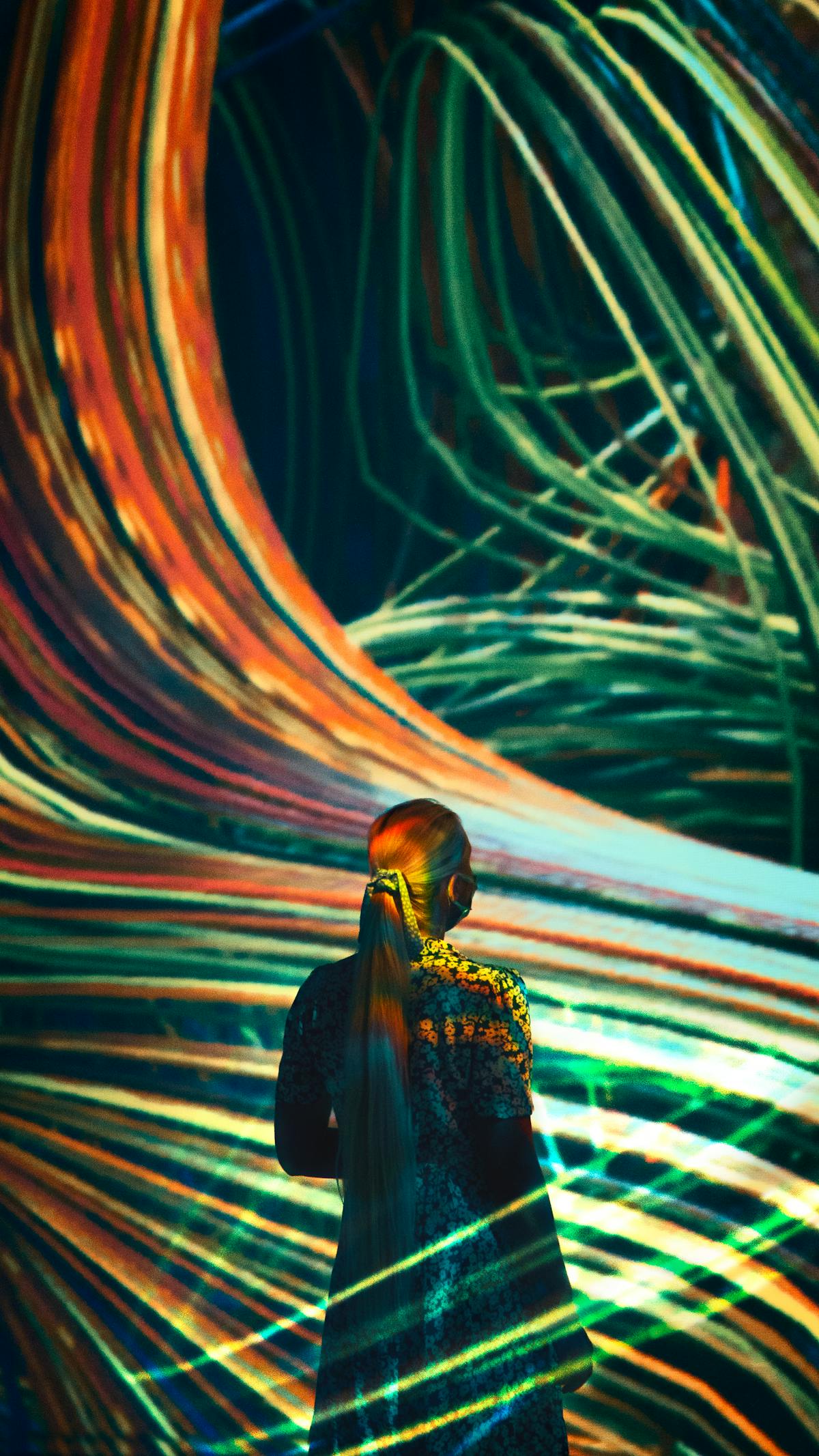 A woman immersed in vibrant digital light art creating a dynamic abstract scene