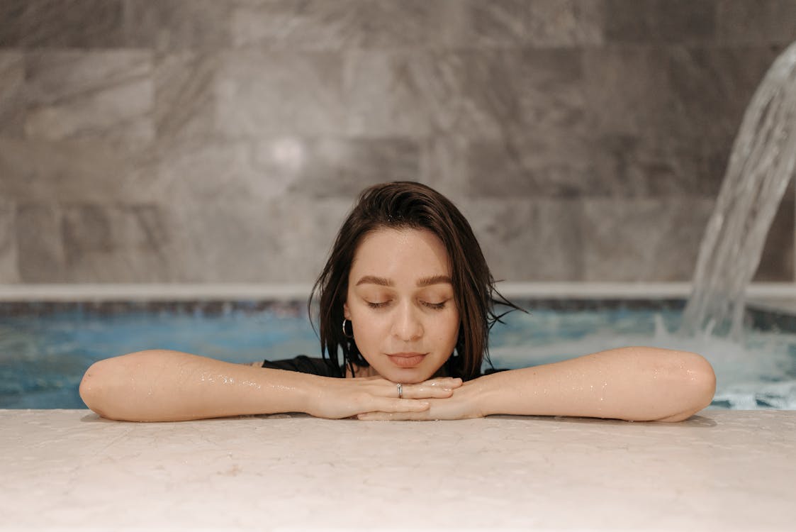 Woman relaxing with closed eyes in an indoor thermal spa pool