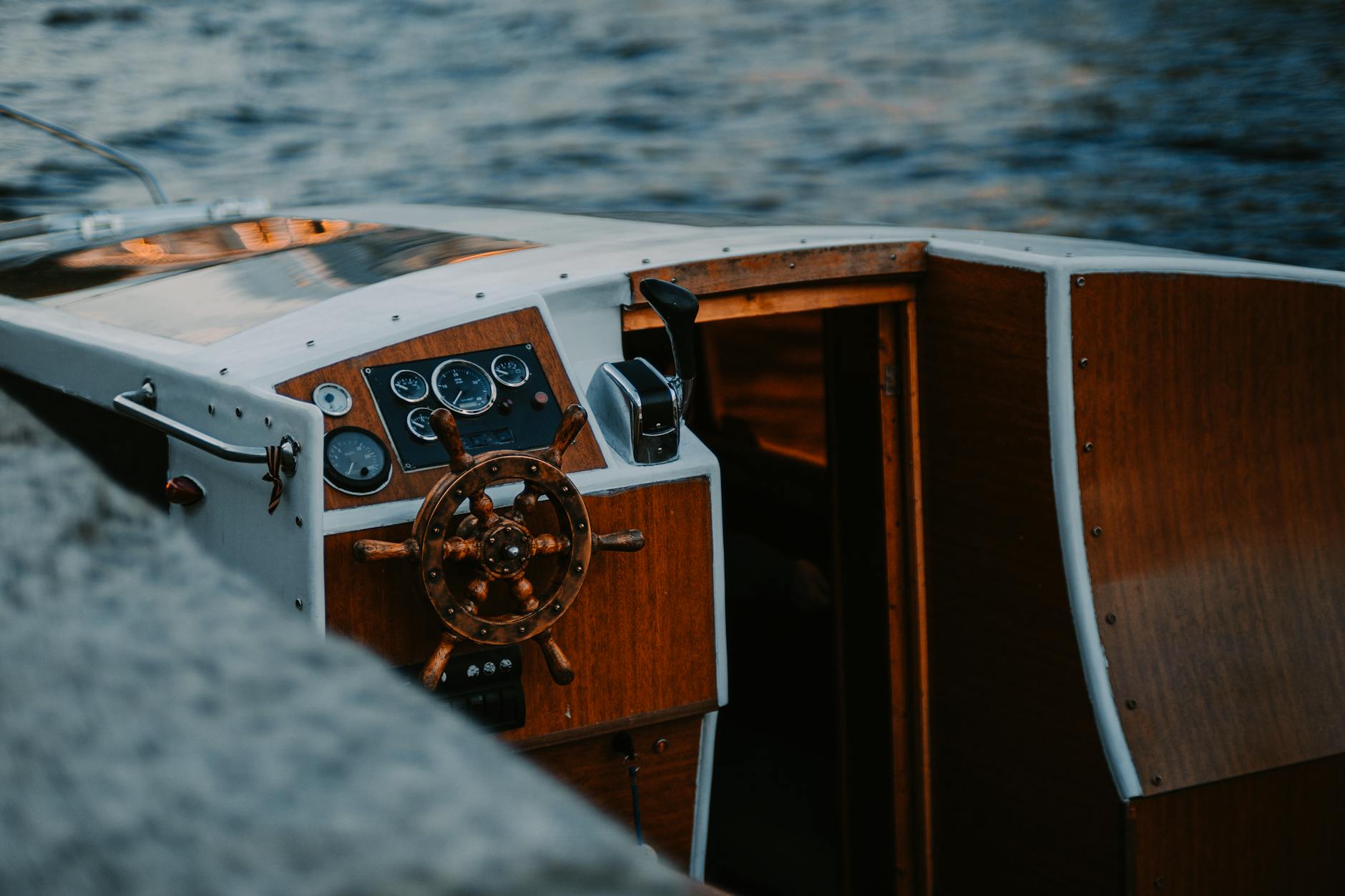 Classic wooden helm on a boat with sunset over the water
