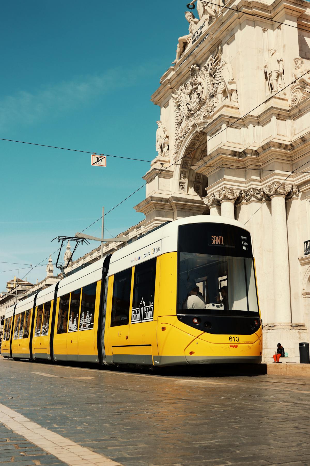 Lisbon yellow tram passing by the historic Praca do Comercio